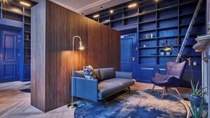 Uma sala de estar moderna com um sofá azul, uma parede de destaque em madeira e uma estante azul.