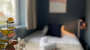 Quarto com cama, janela e quadro pendurado na parede.