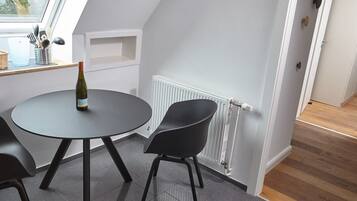 Uma cozinha moderna com uma mesa redonda, duas cadeiras pretas, uma garrafa de vinho e uma janela com vista.