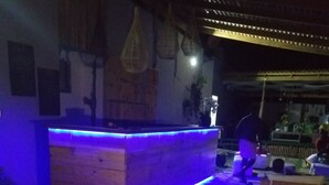 Uma área de bar ao ar livre com balcão de madeira e iluminação azul.