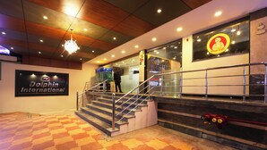 Um saguão de hotel com piso de azulejos, escada com grades de metal e um hidrante nos degraus.