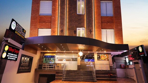 Hotel com design moderno, fachada de tijolos, várias janelas e entrada destacada com degraus até as portas principais.
