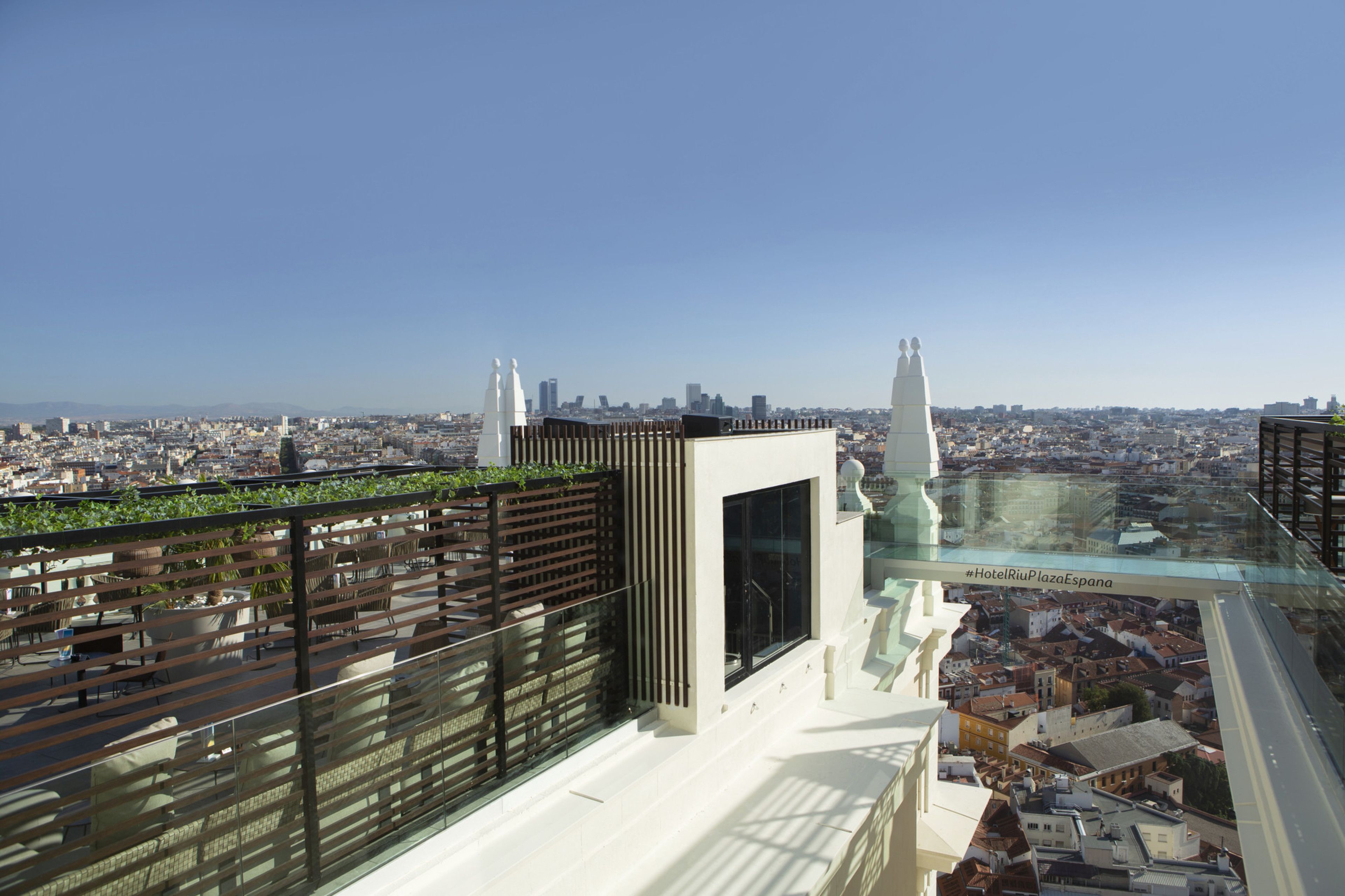 Terraço no telhado com guarda-corpo de vidro, proporcionando vista panorâmica da cidade.