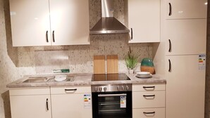Uma cozinha moderna com armários brancos, coifa de aço inoxidável, forno embutido e bancada de granito.