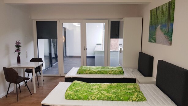 Quarto moderno com duas camas, espaço de refeições e vista para a cidade.