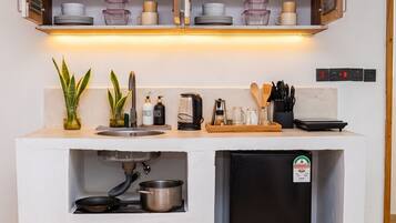 Cozinha compacta com geladeira embutida, pia e bancada com diversos eletrodomésticos e utensílios.