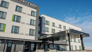 Um hotel Courtyard by Marriott com design moderno, apresentando uma entrada coberta e grandes janelas.
