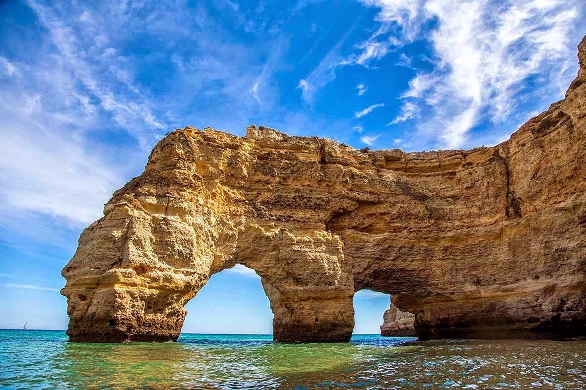 Formação rochosa natural com um grande arco sobre a água.