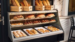 Vitrine de uma padaria com diversos tipos de pães e doces.