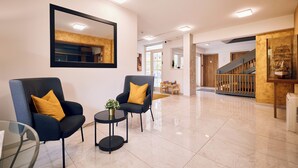 Um hall amplo com dois poltronas, uma mesa pequena e um espelho grande.