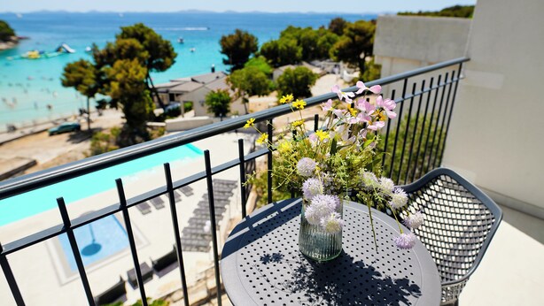 Varanda com vista para uma piscina e o mar.