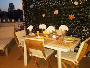 Mesa de jantar posta com cadeiras, uma garrafa de vinho e uma parede decorada com flores.