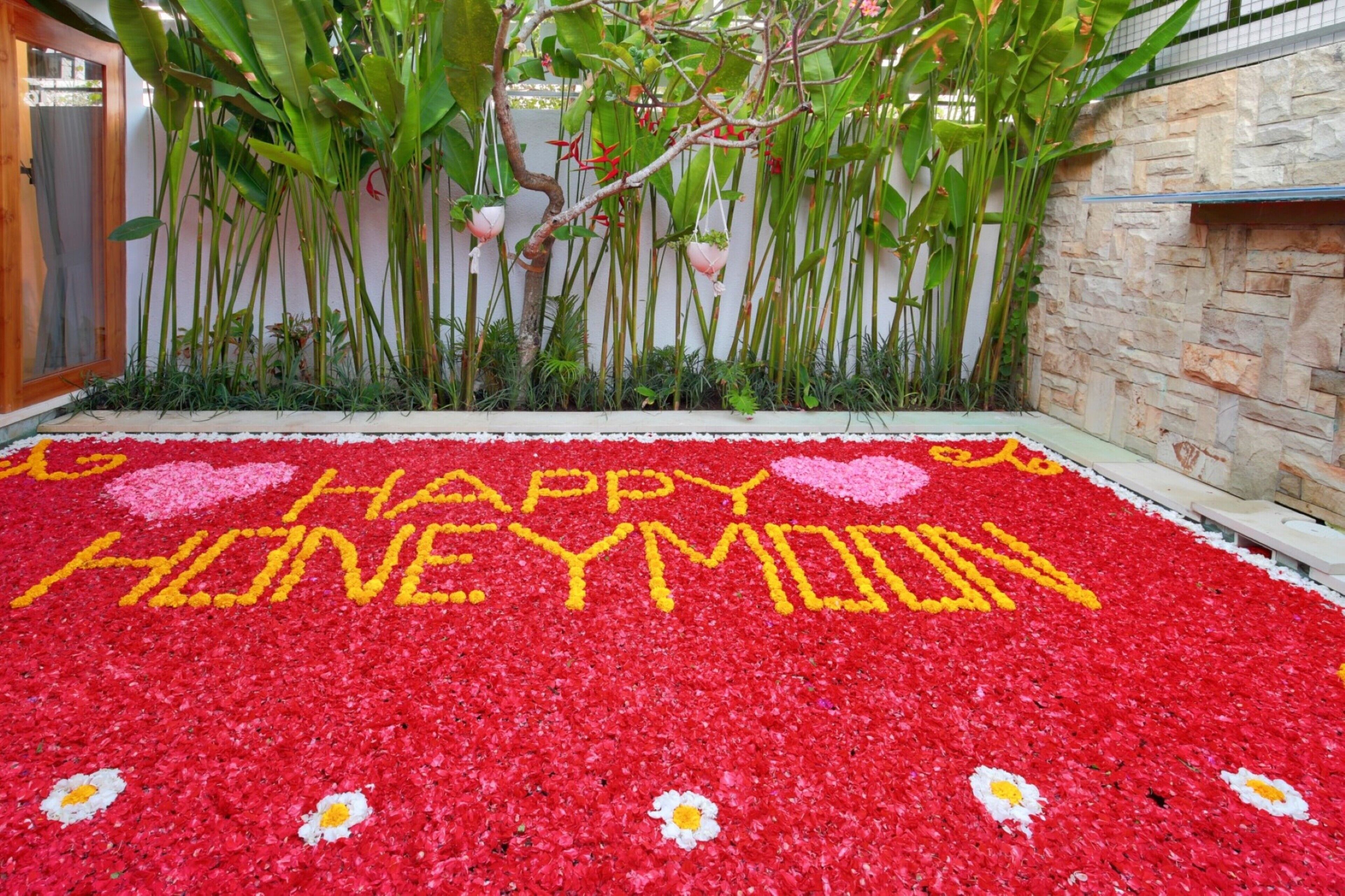Um tapete de flores vermelhas com a inscrição 'HAPPY HONEYMOON' em amarelo.