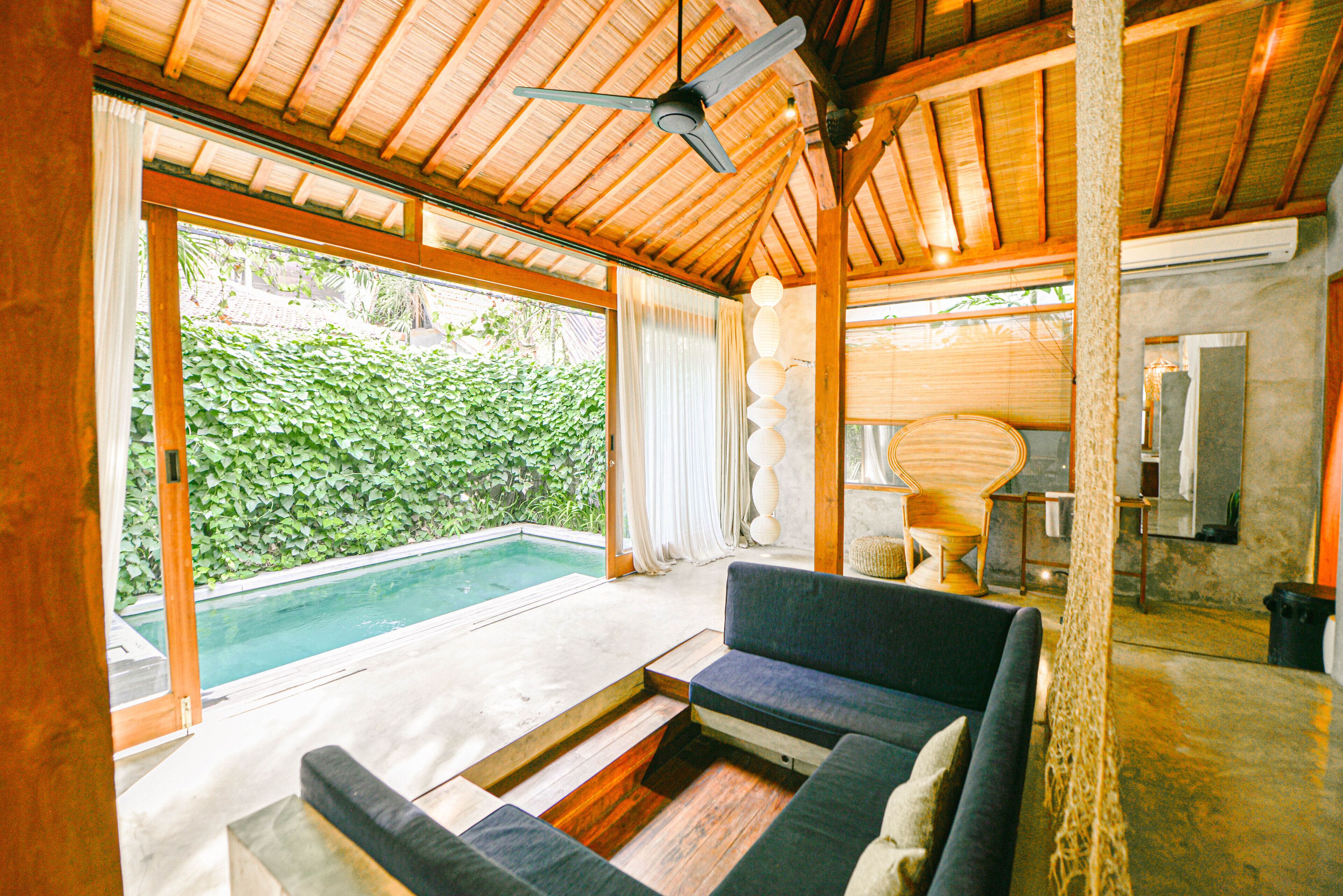 Sala de estar moderna com piscina, teto de madeira e janelas amplas.