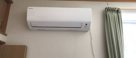 Ar condicionado Daikin branco fixado na parede com teto em painel de madeira.