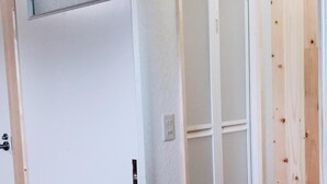 Uma porta branca com uma pequena abertura, uma porta de correr de vidro e um chão de madeira.