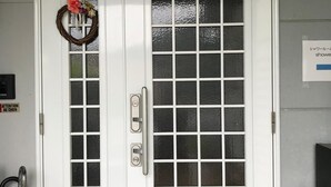 Uma porta branca com painel de vidro e puxador de metal.