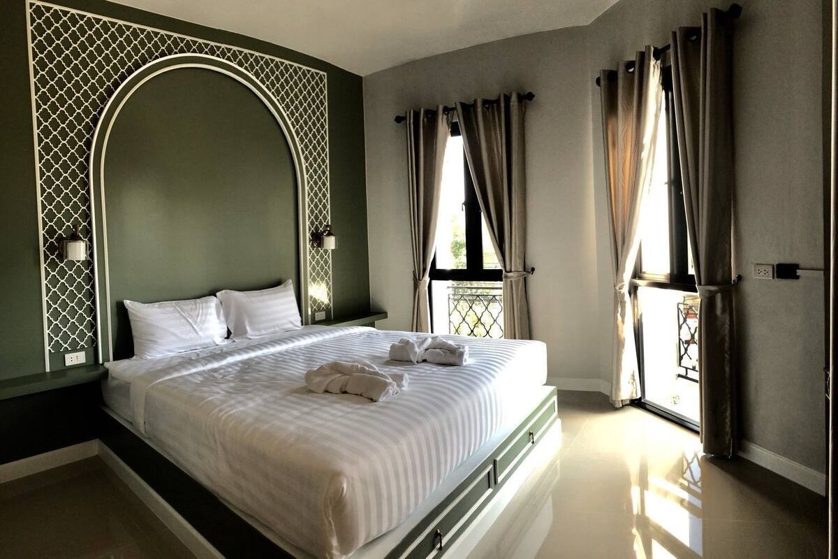 Quarto de hotel com uma cama grande, um painel decorativo na parede e vista pela janela.