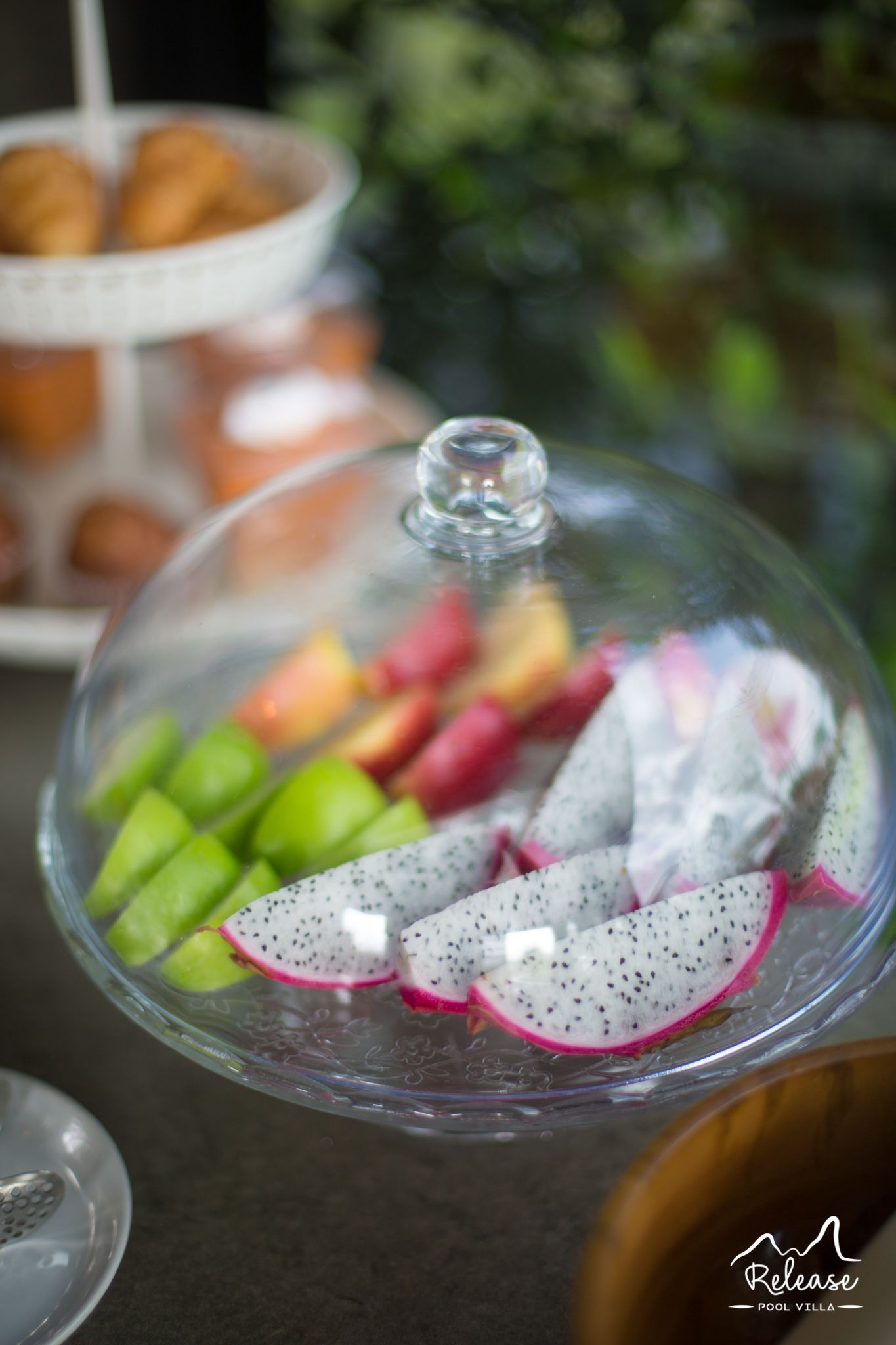 Vitrine de vidro com fruta-dragão fatiada e maçãs verdes.