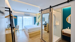 Quarto de hotel moderno com uma cama grande, um closet espaçoso, um banheiro com chuveiro e vista para o exterior.