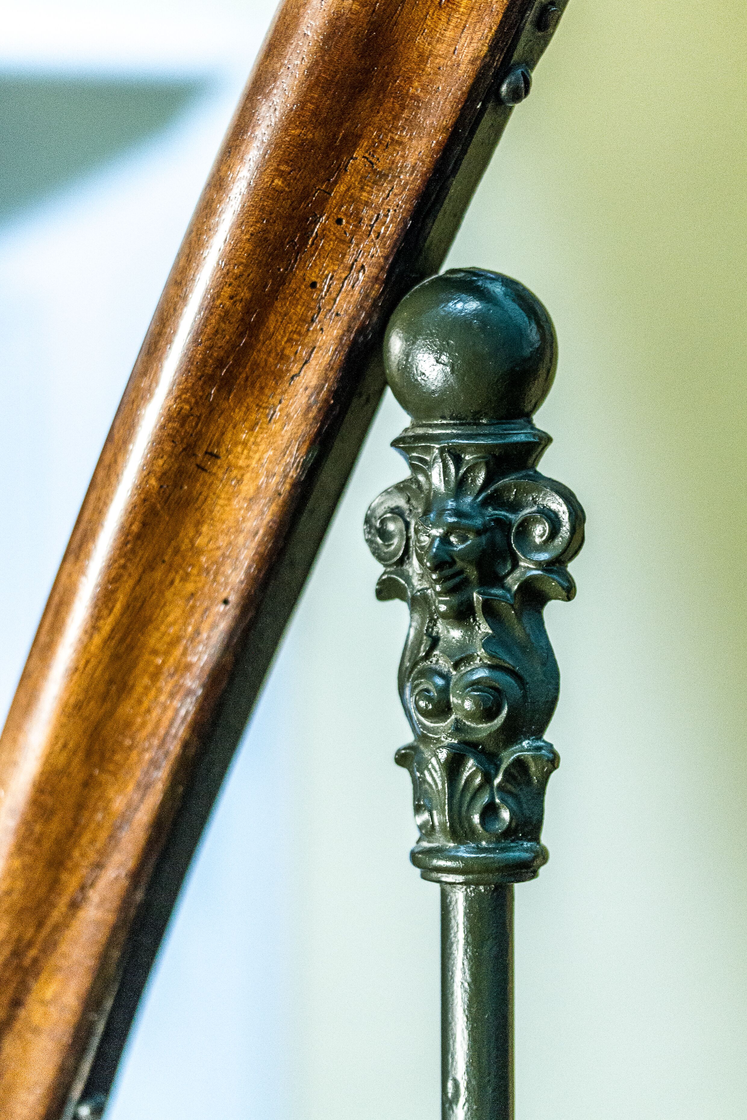 Detalhe de uma perna de cadeira de madeira com um ornamental de metal.