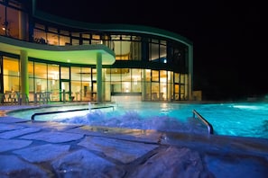Um hotel com uma grande piscina ao ar livre, área de estar coberta e design arquitetônico moderno.