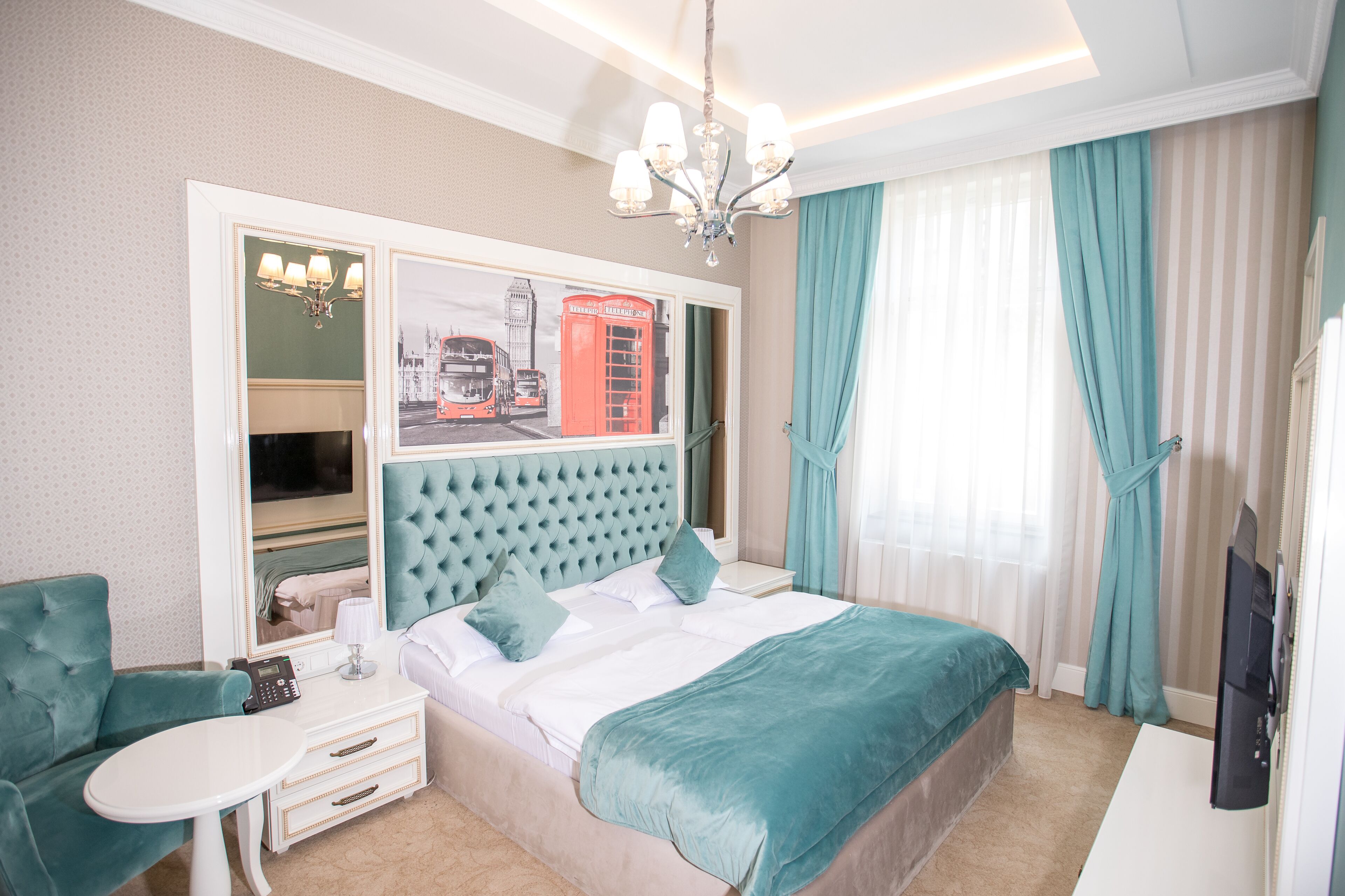 Quarto de hotel com uma cama grande, uma mesa pequena, uma cadeira, televisão e espelho.