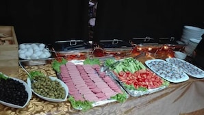 Uma mesa de buffet com diversos tipos de comida, incluindo carnes, legumes e frutas.