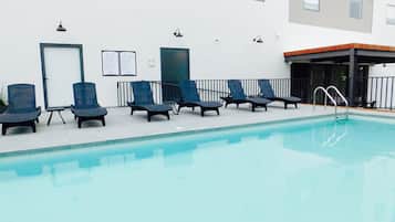 Piscina com espreguiçadeiras e área coberta.