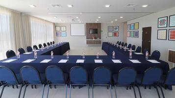 Sala de conferências com uma mesa comprida, cadeiras e garrafas de água.