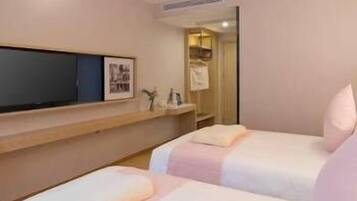 Quarto de hotel com duas camas, uma televisão de tela plana na parede e uma pequena prateleira com objetos.