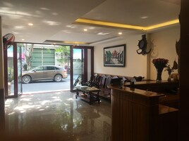 Um hall de hotel com balcão de recepção, área de estar e uma grande janela com vista para a rua.