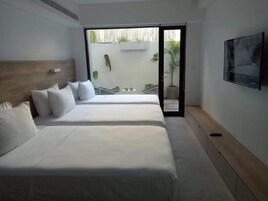 Quarto de hotel com duas camas, televisão e porta de vidro deslizante para área externa.