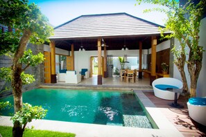 Uma área externa coberta com piscina, assentos e espaço para refeições.