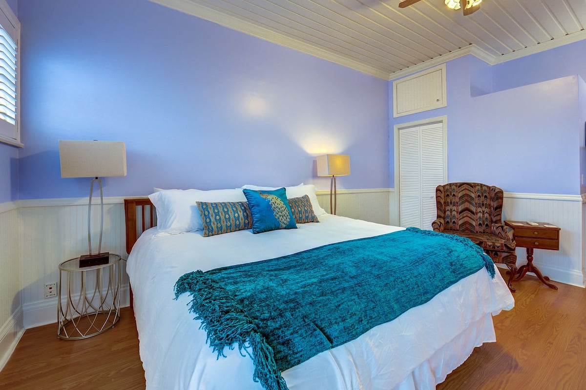 Quarto com uma cama, duas luminárias de cabeceira, uma cadeira e uma mesa de cabeceira.