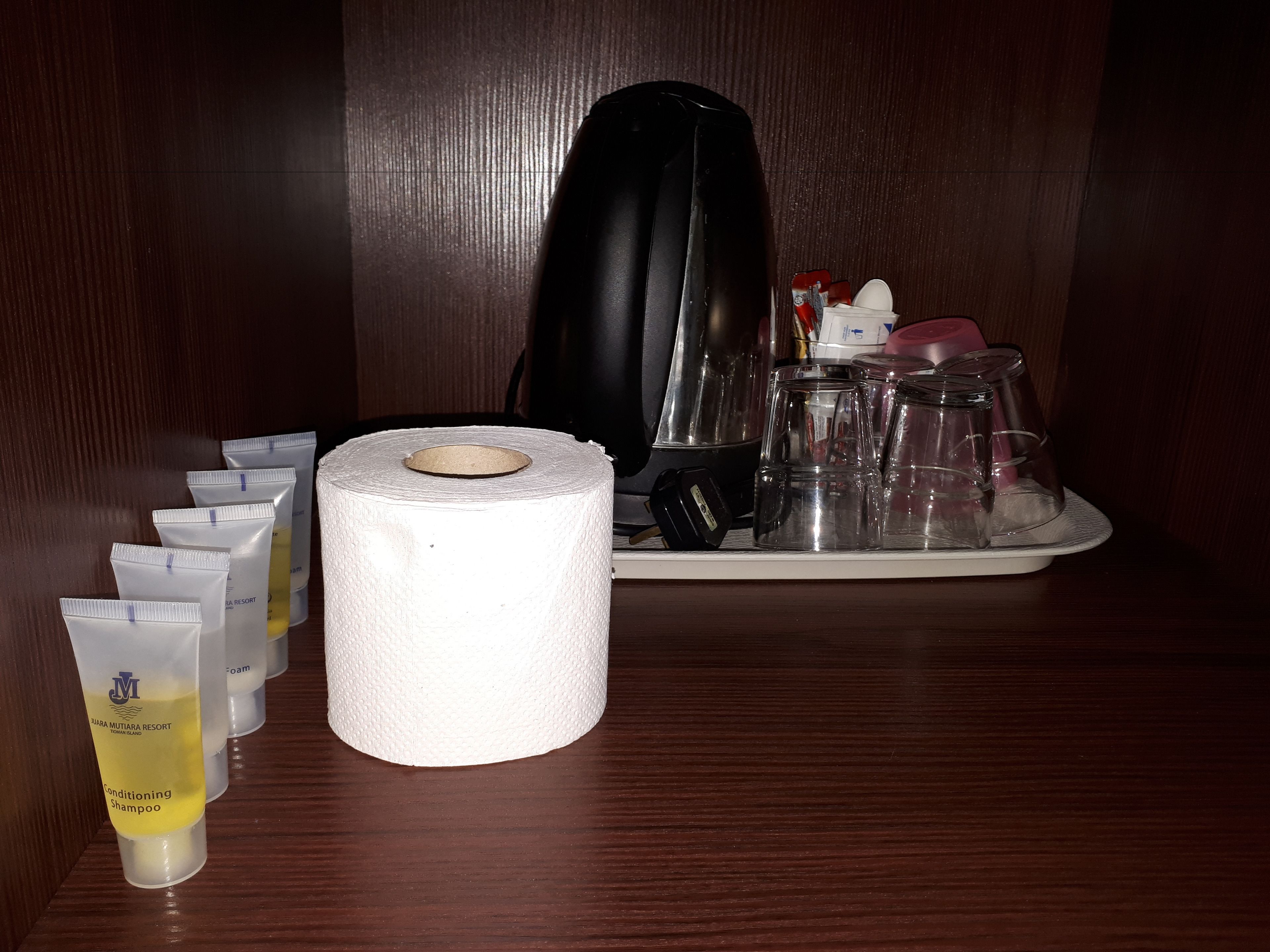 Casa de banho com amenities, incluindo rolo de papel higiénico, champô e máquina de café.