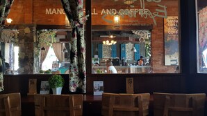Interior de restaurante com paredes de tijolo, mobiliário de madeira e vista para a rua.