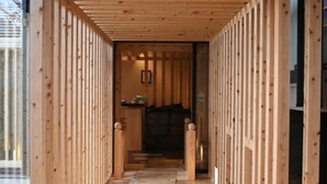 Um corredor de madeira estreito com teto e paredes de madeira, que leva a um quarto com cama e cômoda.