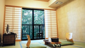 Um quarto japonês tradicional com piso de tatame, uma porta deslizante e vista para uma varanda com grade de madeira.