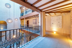 Interior com vários níveis, varanda, iluminação decorativa e parede com design abstrato.
