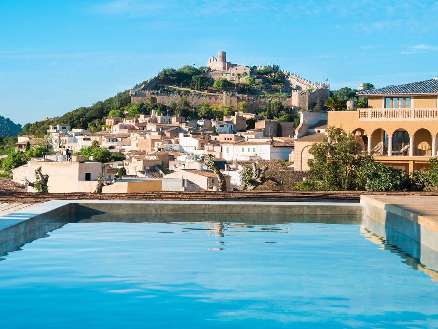 Piscina com vista para uma cidade histórica e um castelo no topo de uma colina.