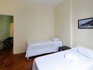 Quarto com duas camas de solteiro, uma mesinha e uma cadeira.