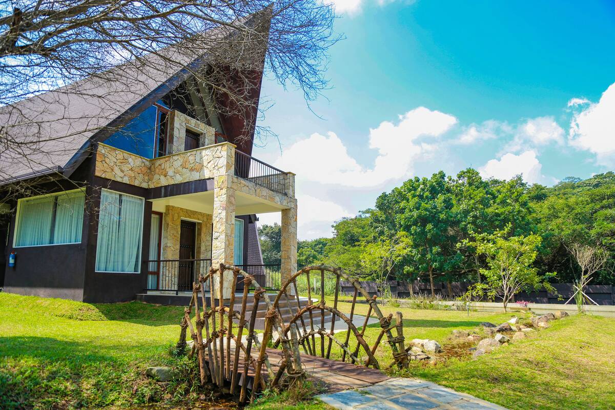 Uma casa moderna com fachada de pedra, varanda e um gramado bem cuidado.