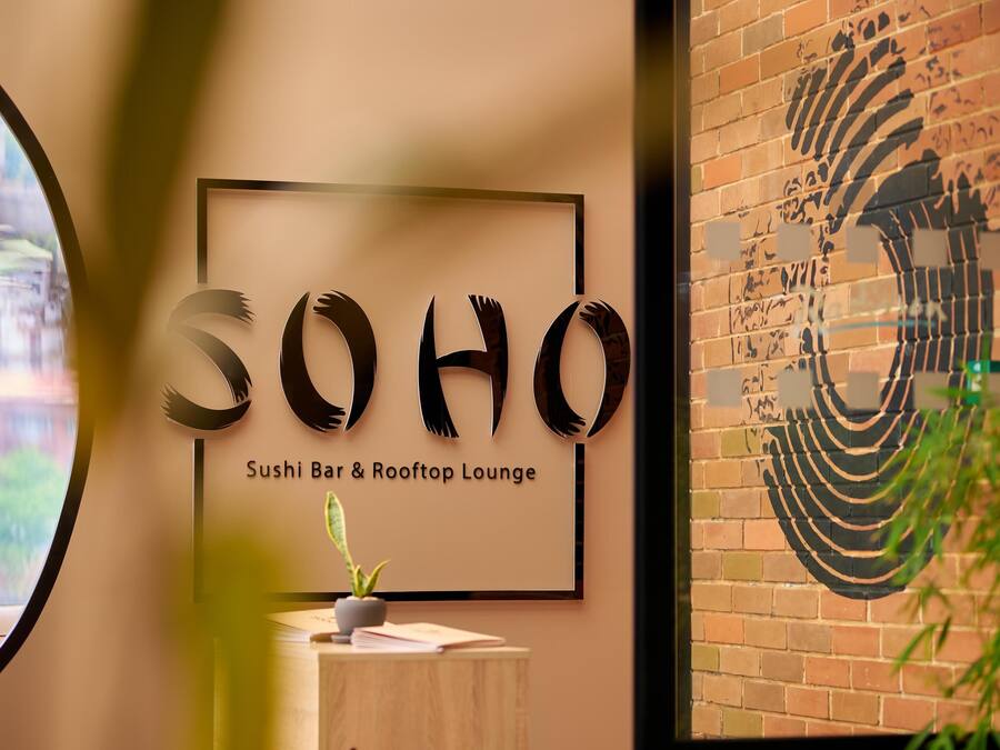 Paredes com o nome 'SOHO Sushi Bar & Rooftop Lounge' e uma obra de arte decorativa.