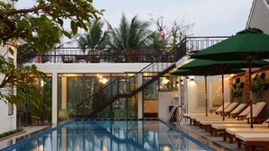Piscina com espreguiçadeiras, escada e varanda com área de estar ao ar livre.