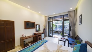 Quarto de hotel com cama, escrivaninha, televisão e vista para o exterior.