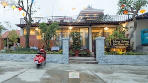 Um hotel com uma placa indicando 'Sông Sông River Waves Villa' e uma scooter estacionada em frente.