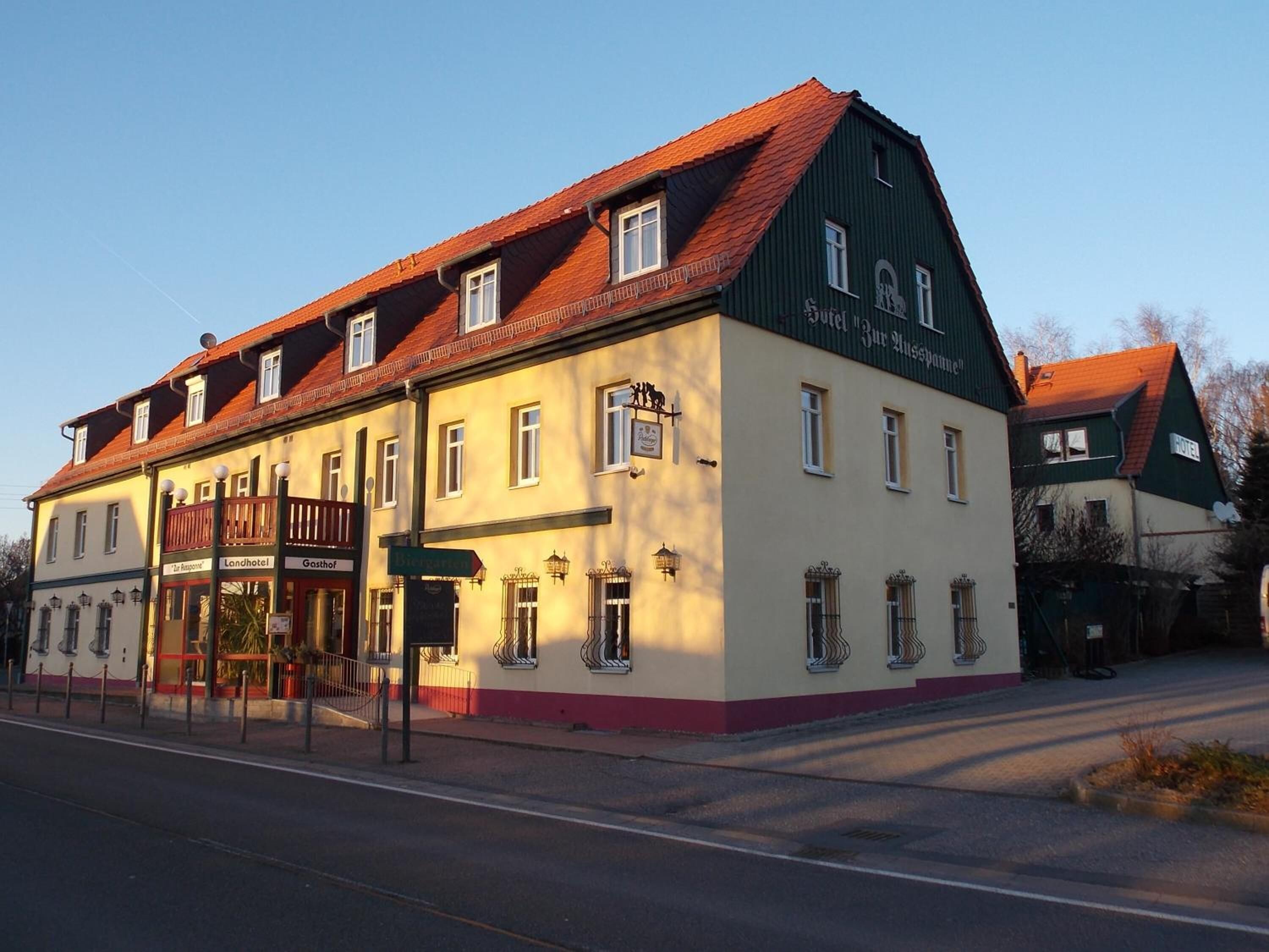 Um edifício tradicional com telhado verde e várias janelas, identificado como hotel.