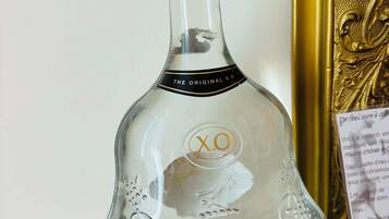 Uma garrafa de vidro transparente com uma etiqueta que diz 'Hennessy' e 'X.O' sobre uma superfície de mármore.