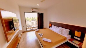 Quarto de hotel com cama, televisão, varanda e janela.